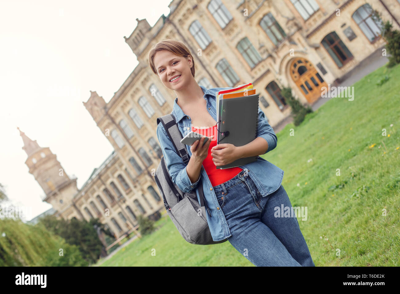 Young female student carrying backpack at university campus walking ...