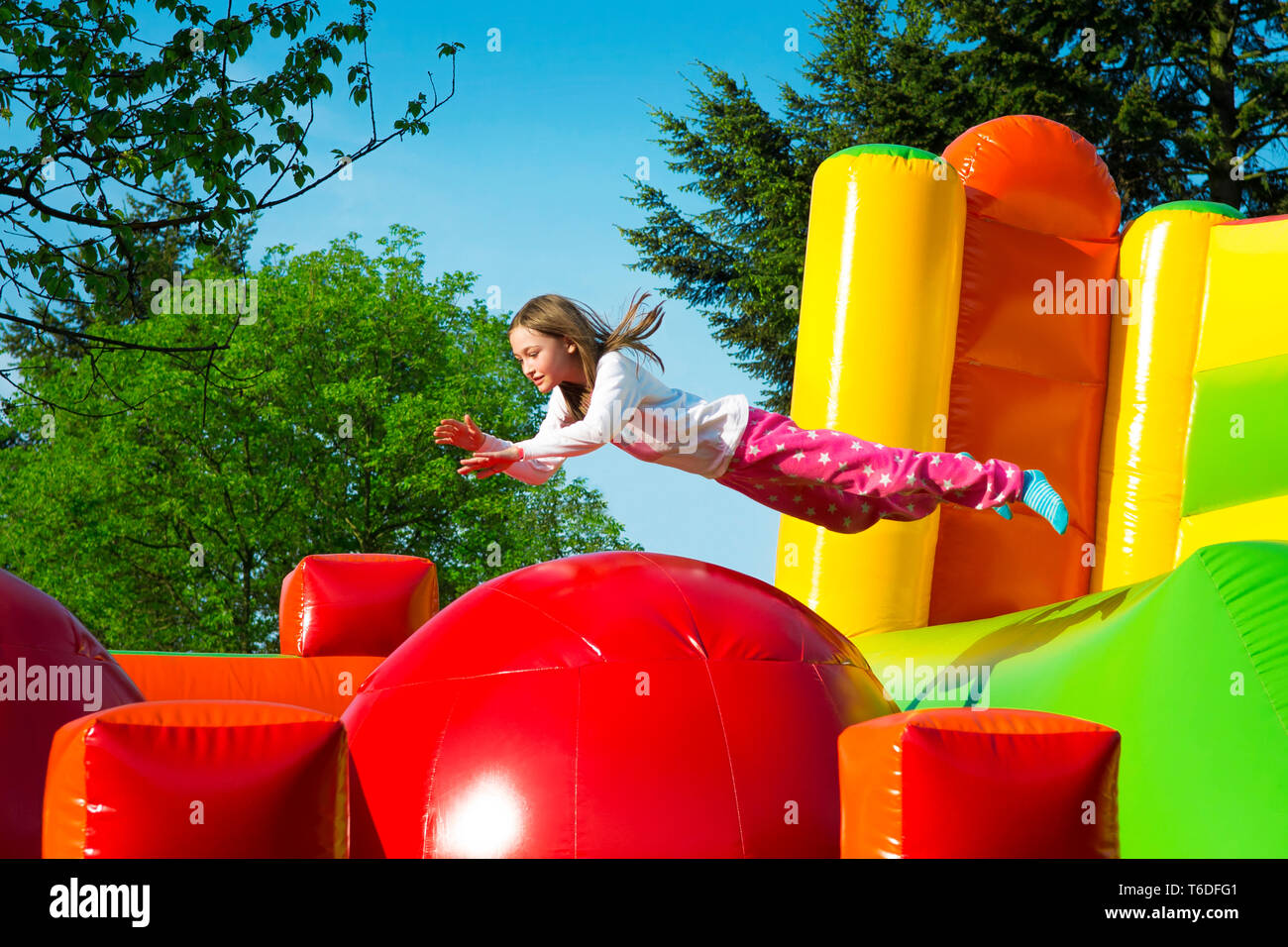 Happy little girl having lots of fun while jumping from ball to ball on ...