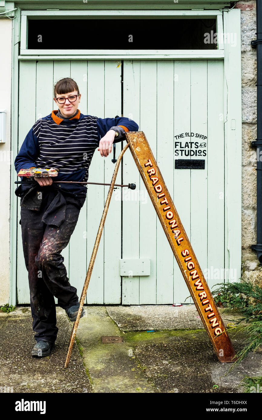 Woman leaning on a ladder, outside a property with a large door holding ...