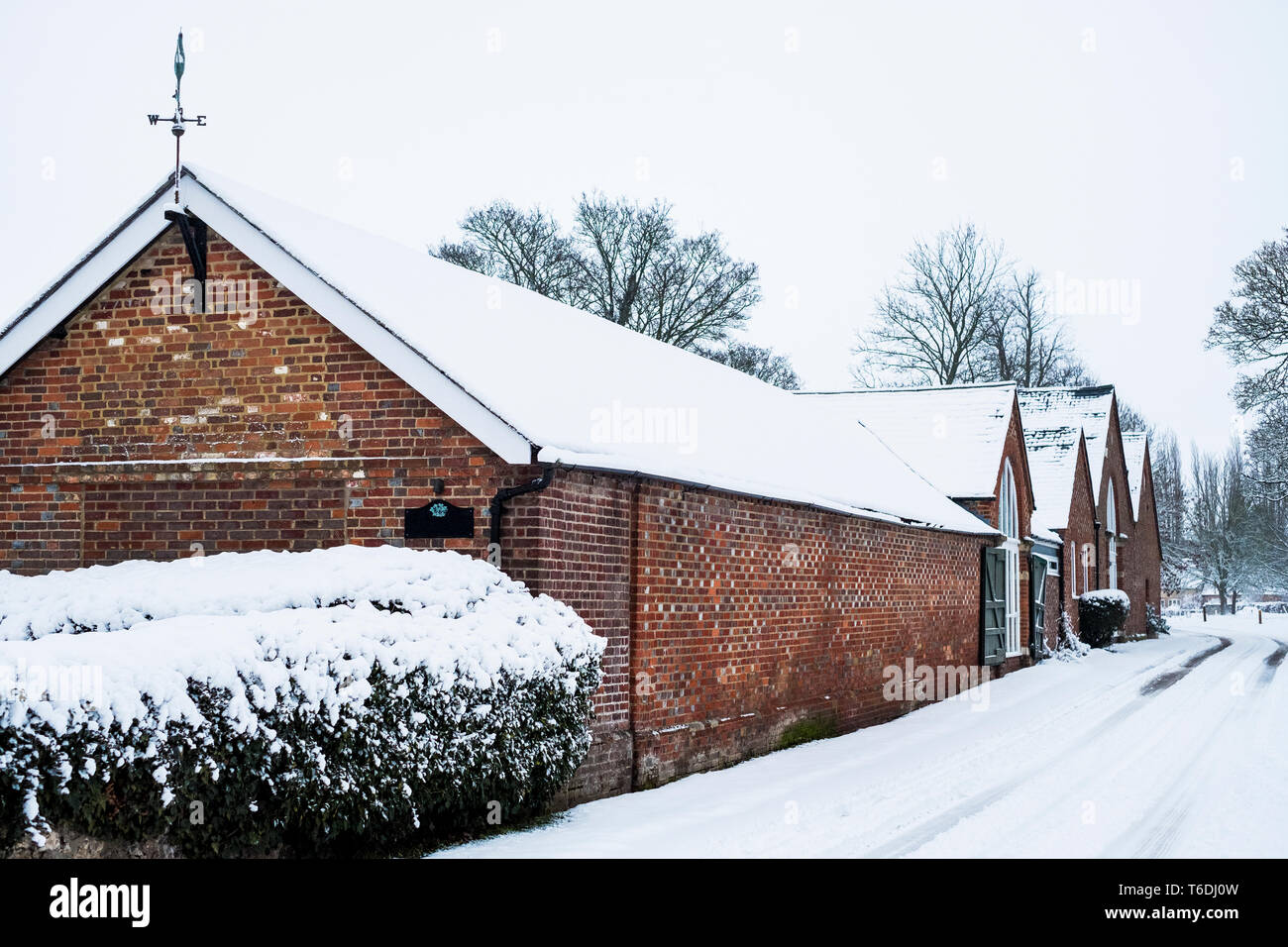 Exterior view of red brick cottages with snow-covered roofs along a ...