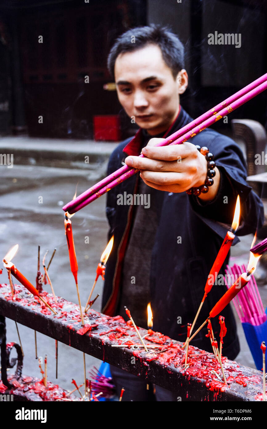 Chengdu, Sichuan province, China : A young man burns incense joss ...