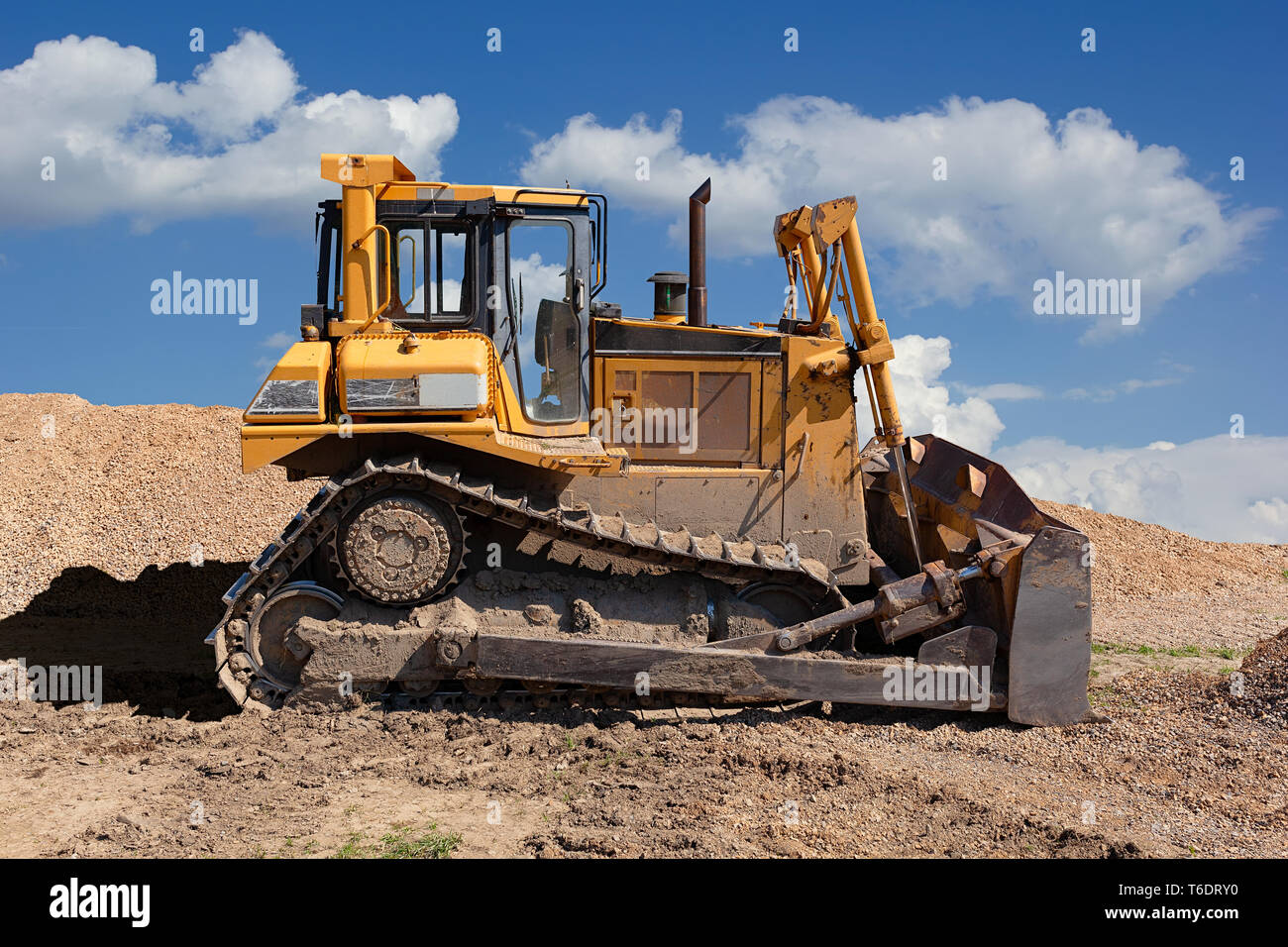 Yellow dozer on a dirt terrain with blue sky with clouds in the ...