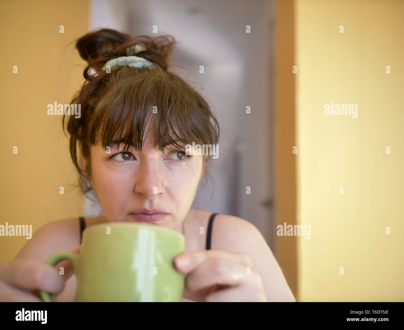 Sleepy young attractive woman with a cup of coffee in the morning at ...