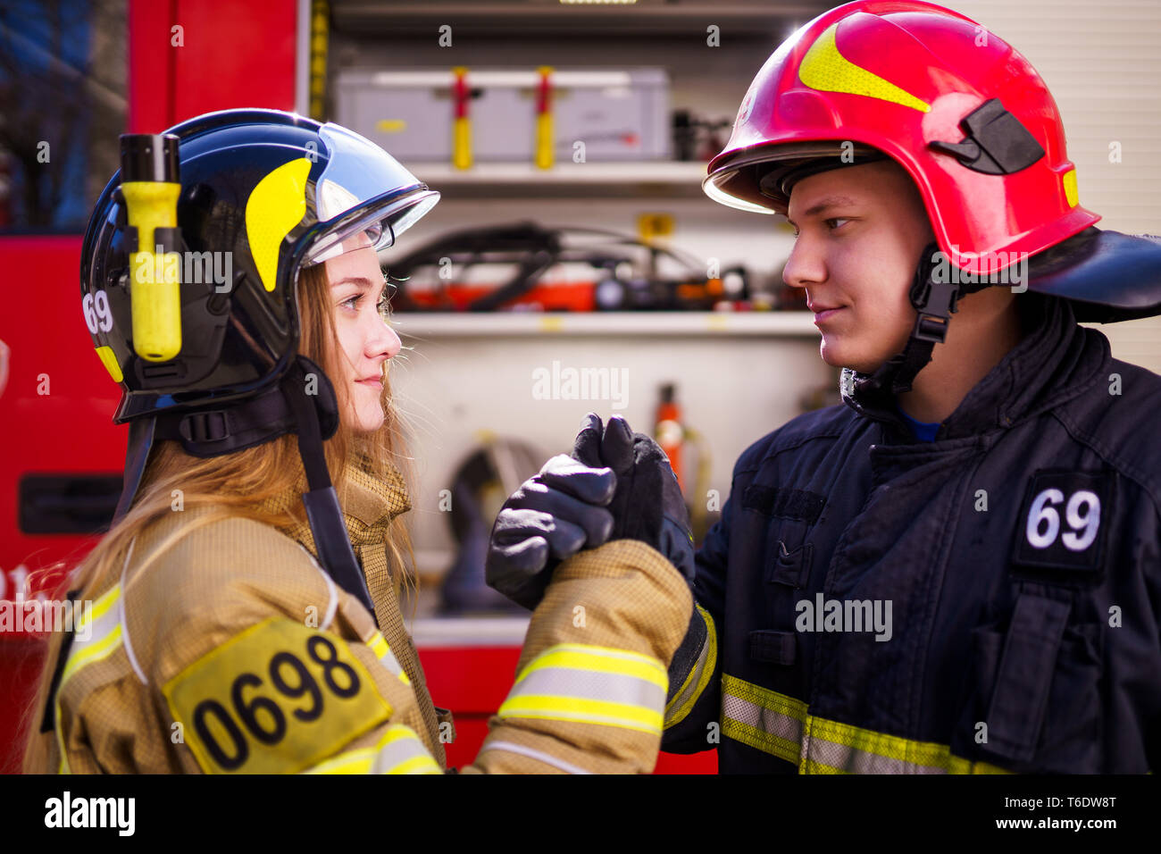 Side view of woman firefighter and man wearing helmets doing a ...