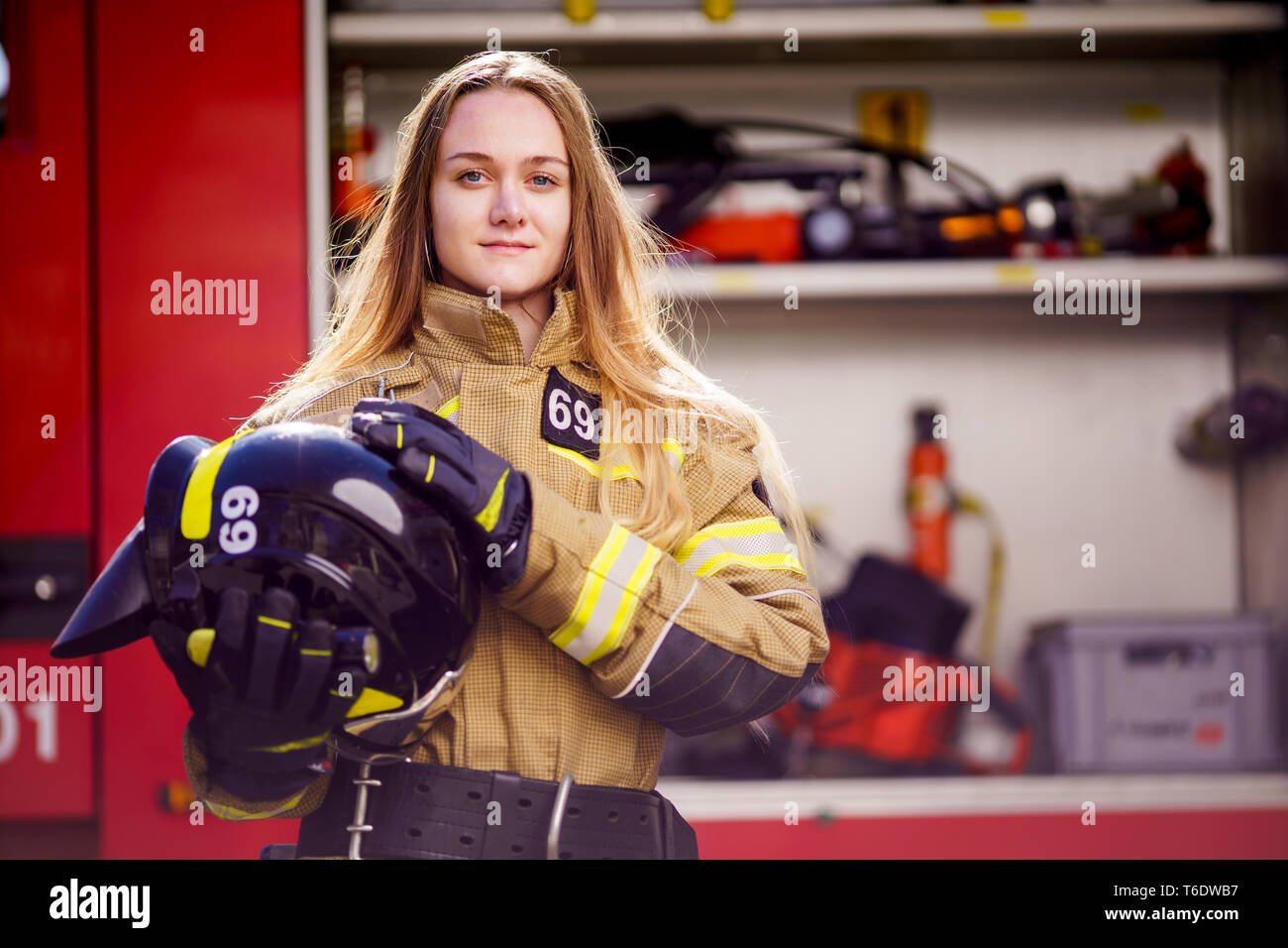 Photo of woman firefighter with helmet in her hands standing near fire ...