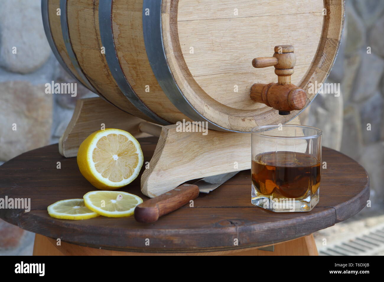 A glass of brandy with sliced lemon near the barrel Stock Photo - Alamy