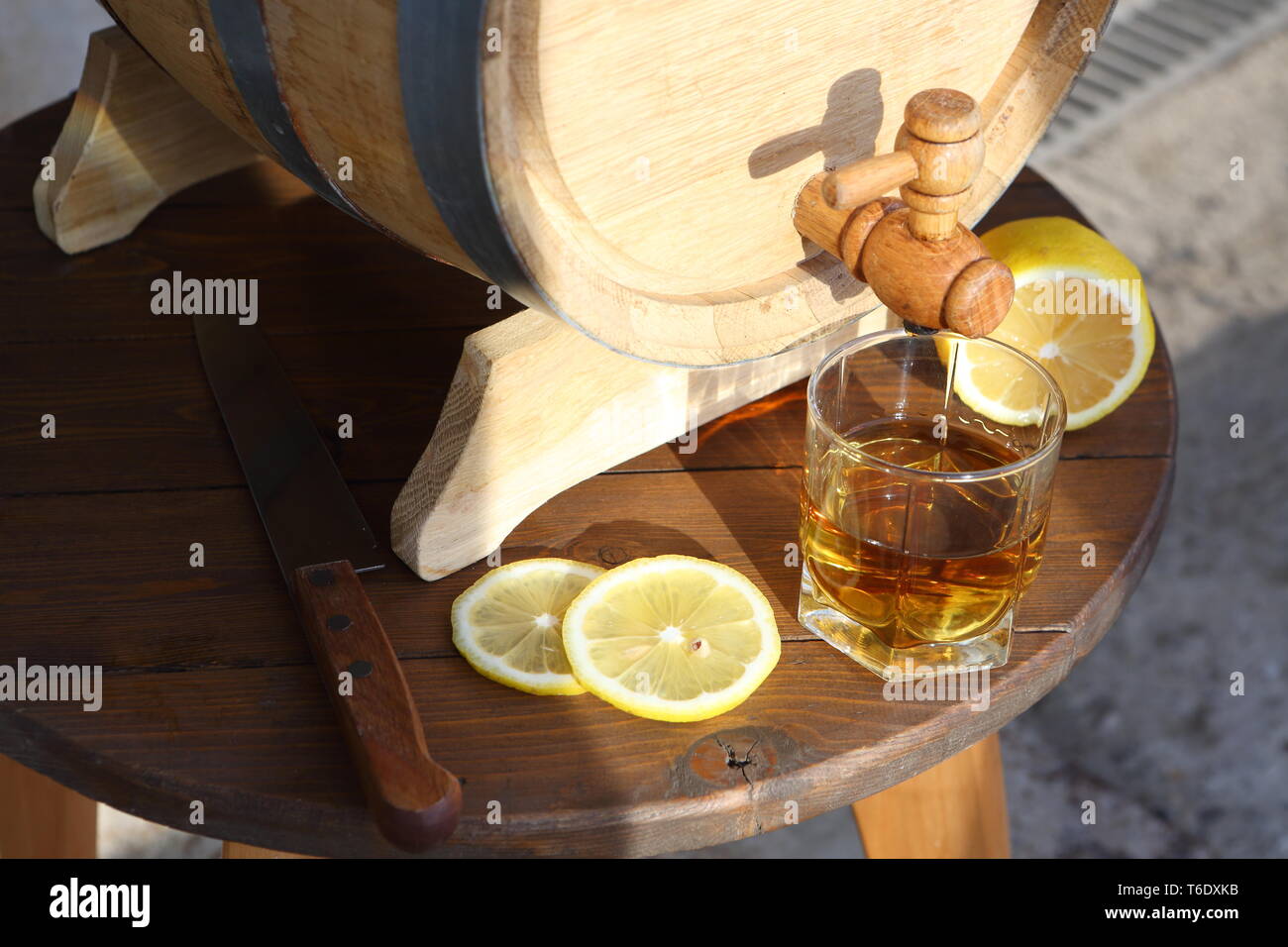 A glass of brandy with sliced lemon near the barrel Stock Photo - Alamy