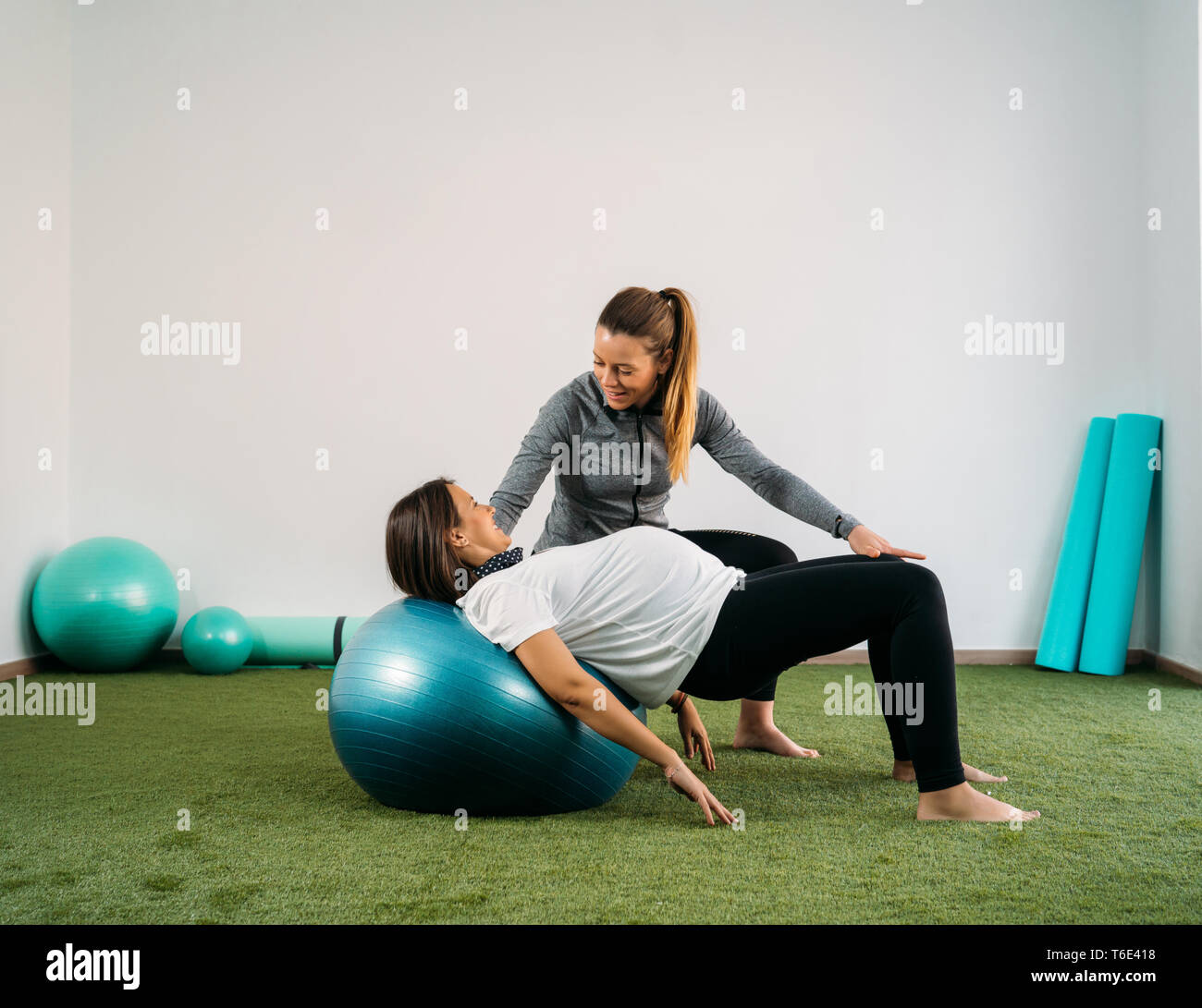 Pregnant woman doing fitness ball and pilates exercise with coach ...