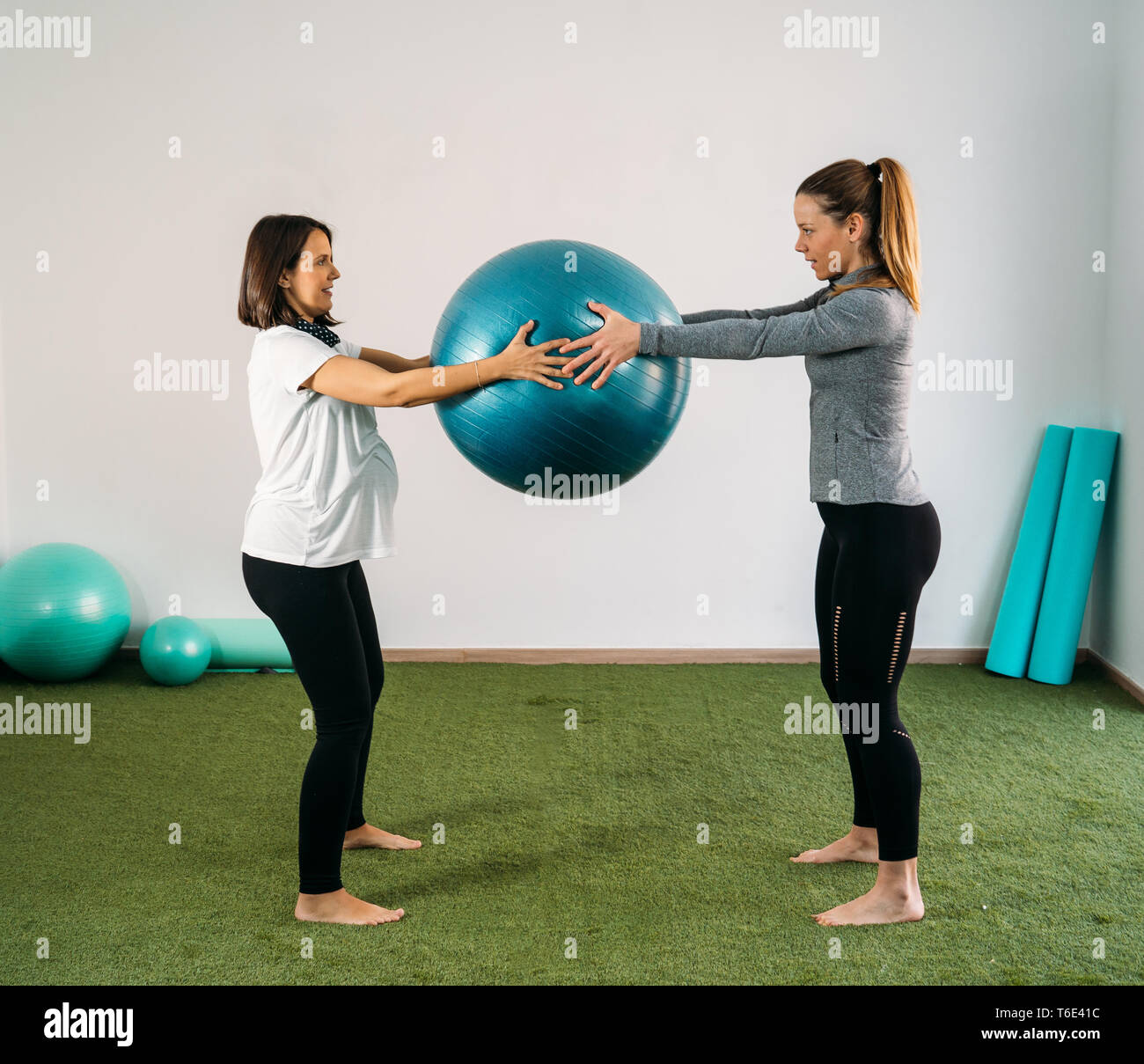 Pregnant woman doing fitness ball and pilates exercise with coach ...
