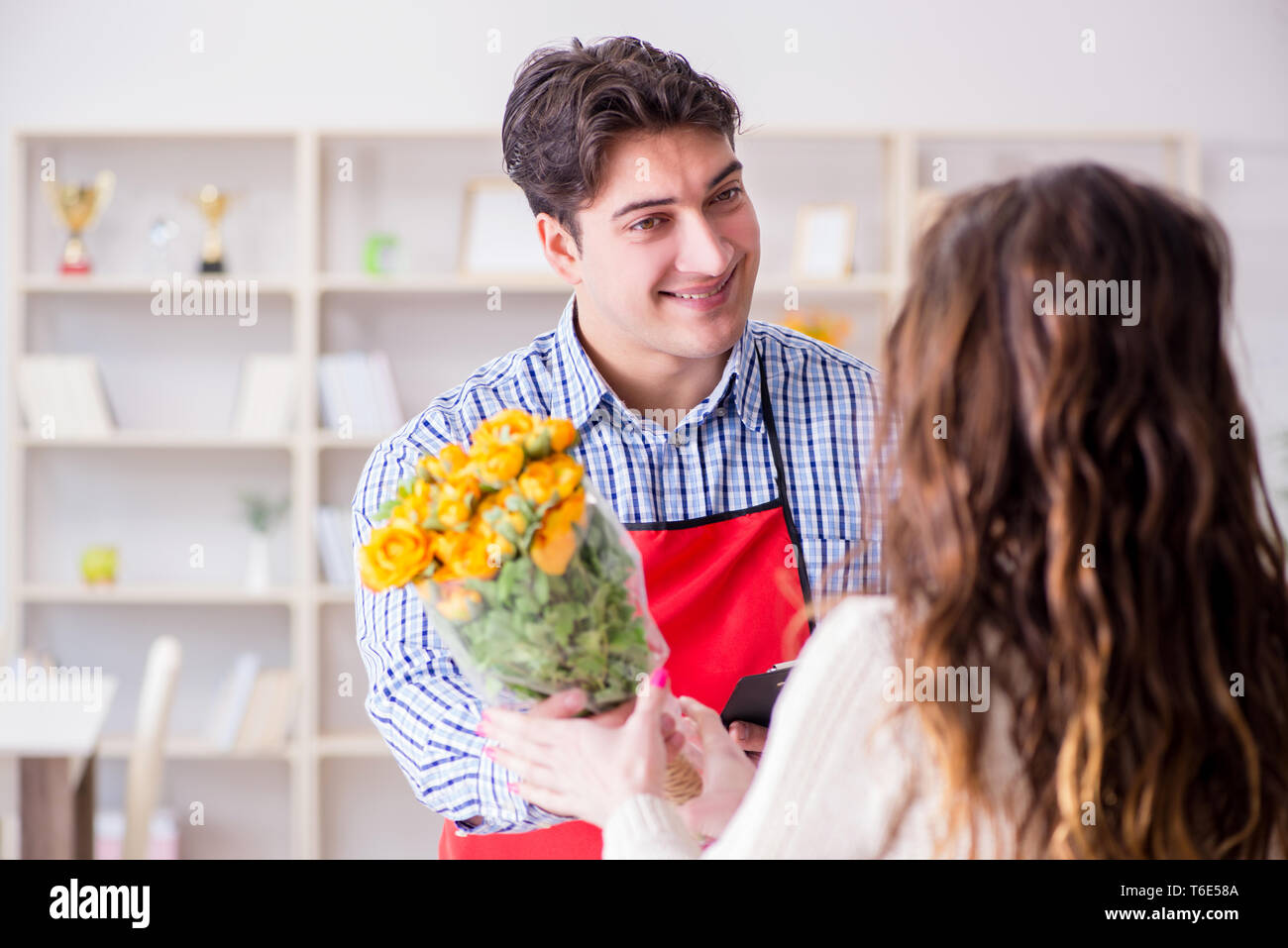Flower shop assistant selling flowers to female customer Stock Photo ...