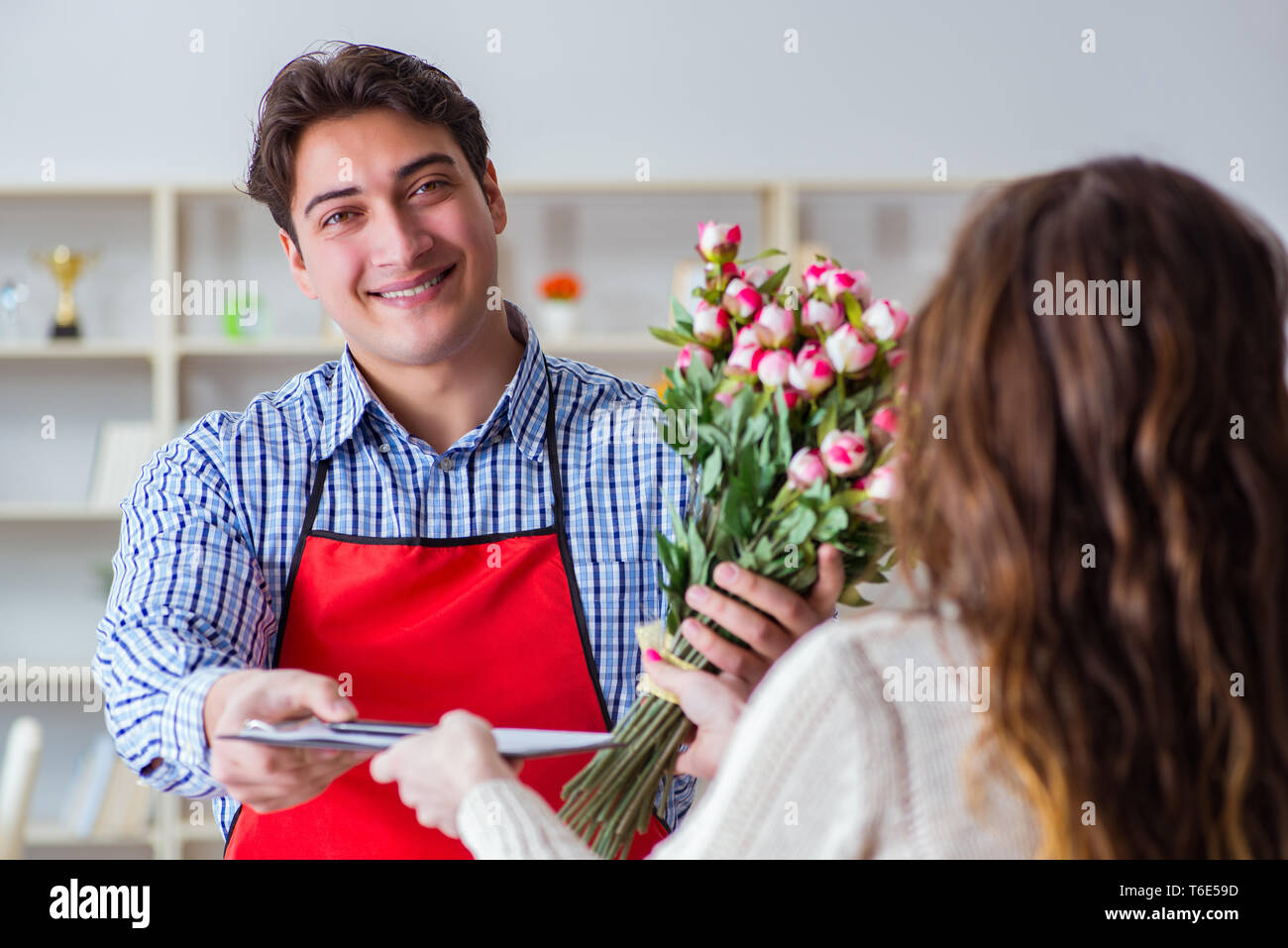 Flower shop assistant selling flowers to female customer Stock Photo ...
