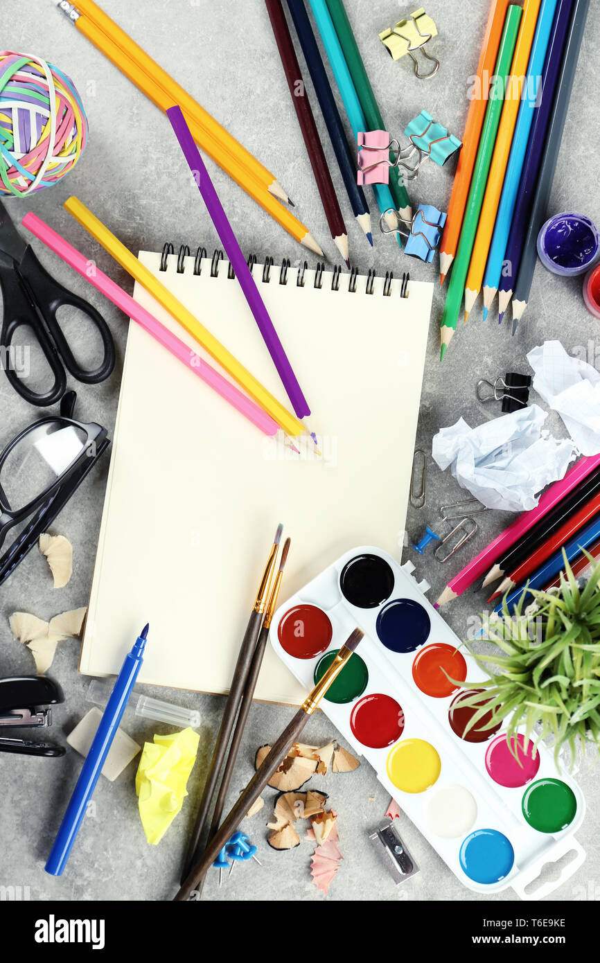 Workplace composition with paint, notebook and color pencils on table ...