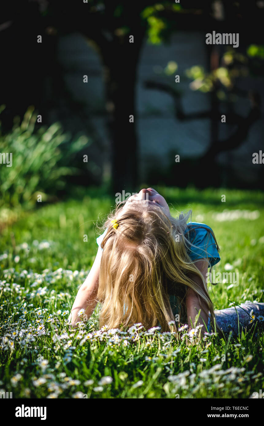 adorable blond girl having fun in spring dandelion field Stock Photo ...