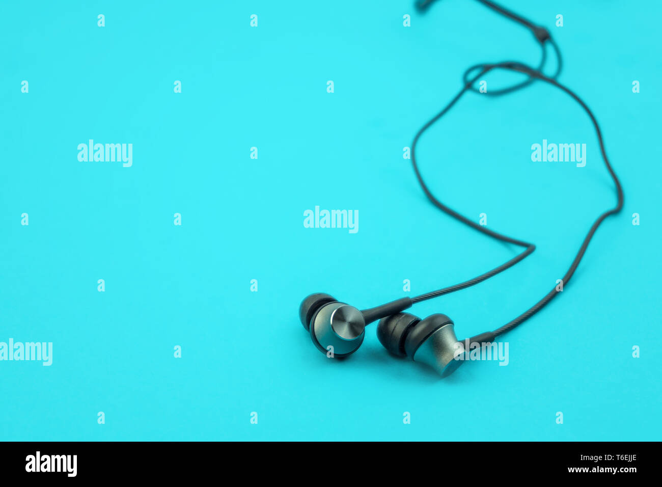 Metal ear buds and wires on blue background, low angle with copy space ...