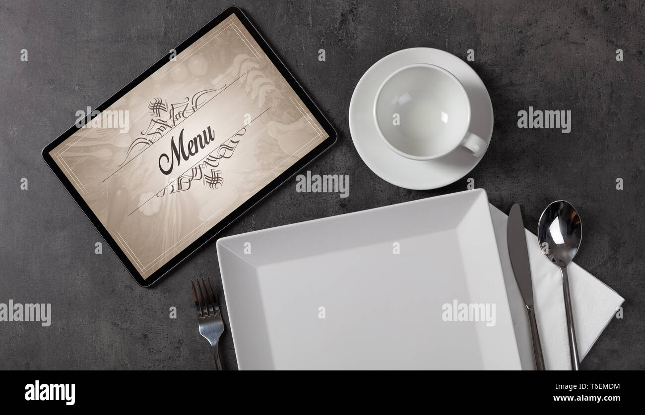 Tablet with stylish restaurant logo and laid table Stock Photo - Alamy