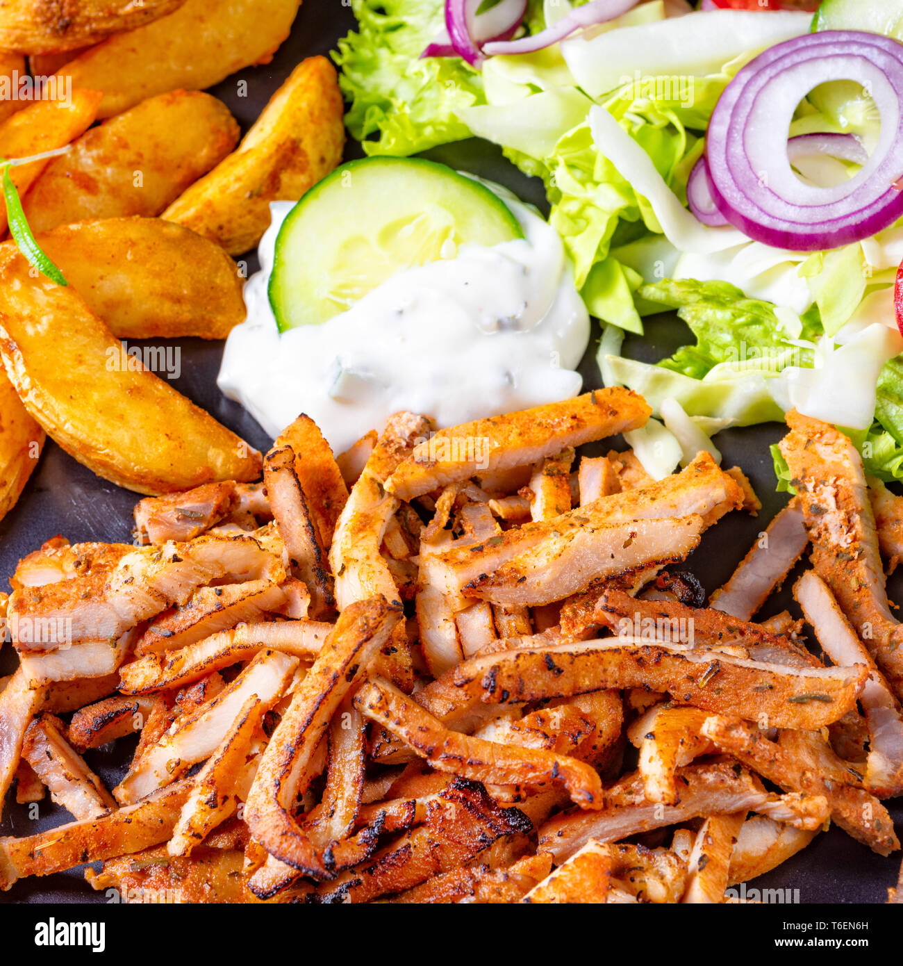 Rustic gyros plate it green salad and potato wedges Stock Photo - Alamy