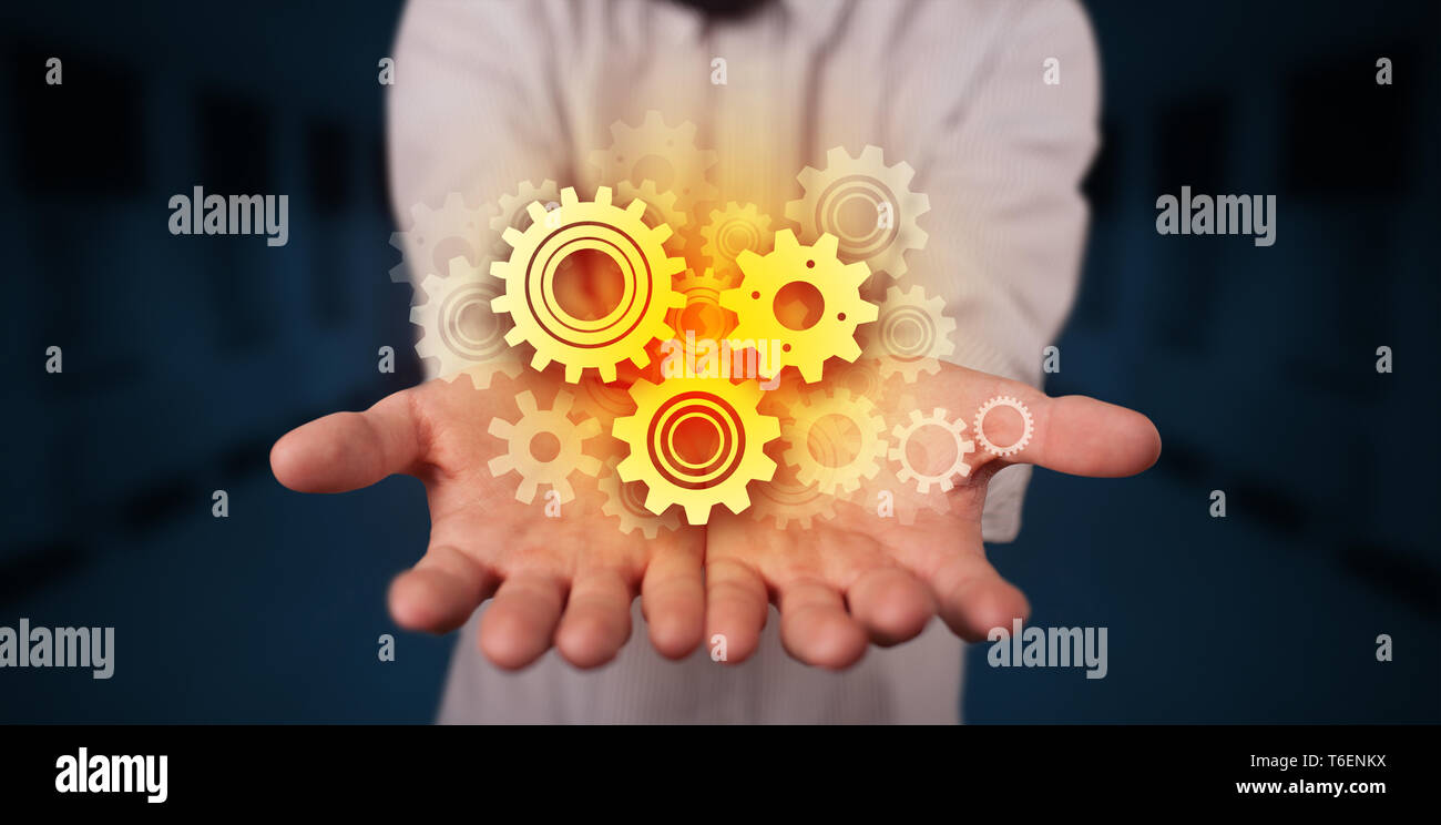 Hand holding gears in his hand Stock Photo - Alamy