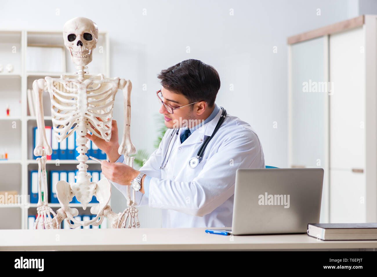 Yong male doctor with skeleton isolated on white Stock Photo - Alamy
