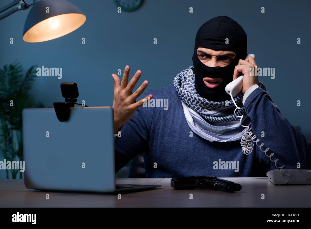 Terrorist burglar with gun working at computer Stock Photo - Alamy