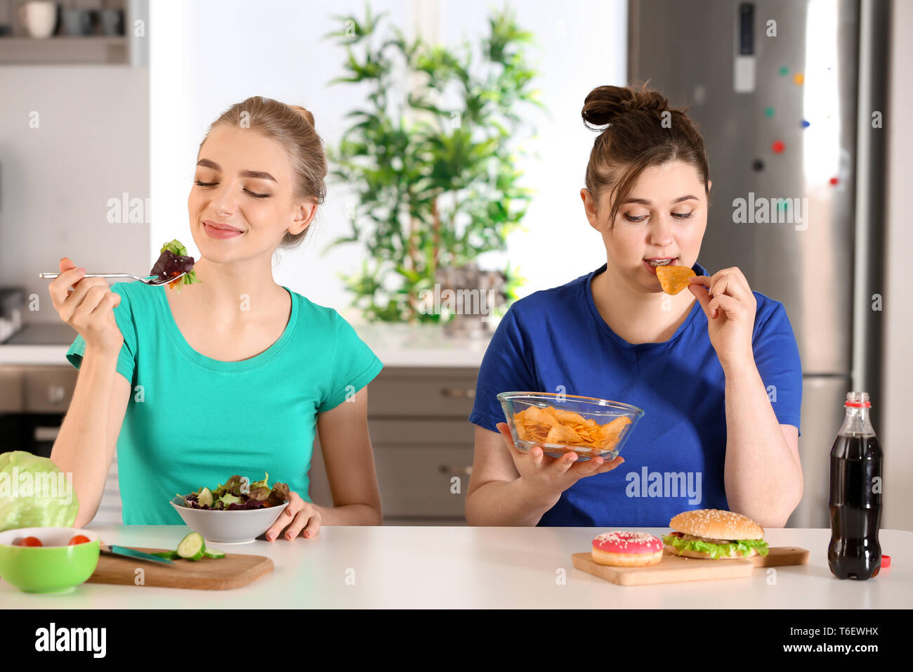 Women eating at table in kitchen. Choice between diet and unhealthy ...