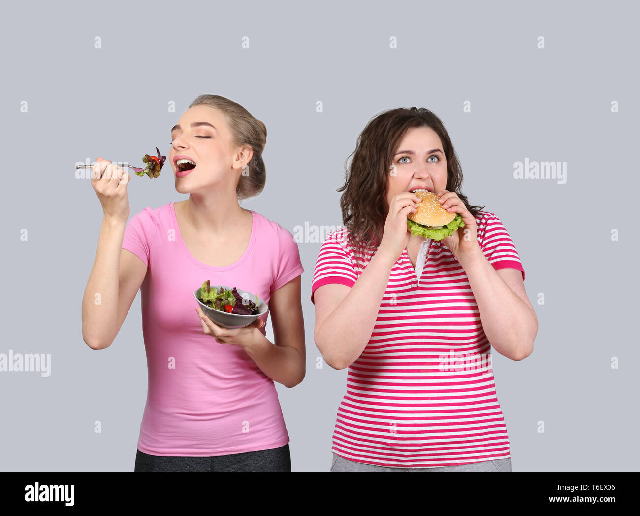 Women eating on grey background. Choice between diet and unhealthy food ...