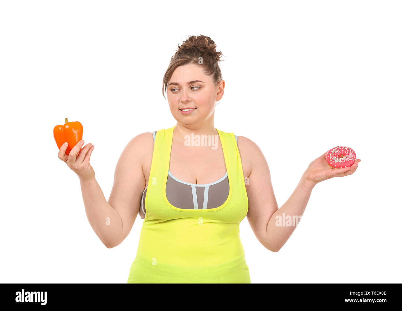 Young stout woman choosing between pepper and donut on white background ...