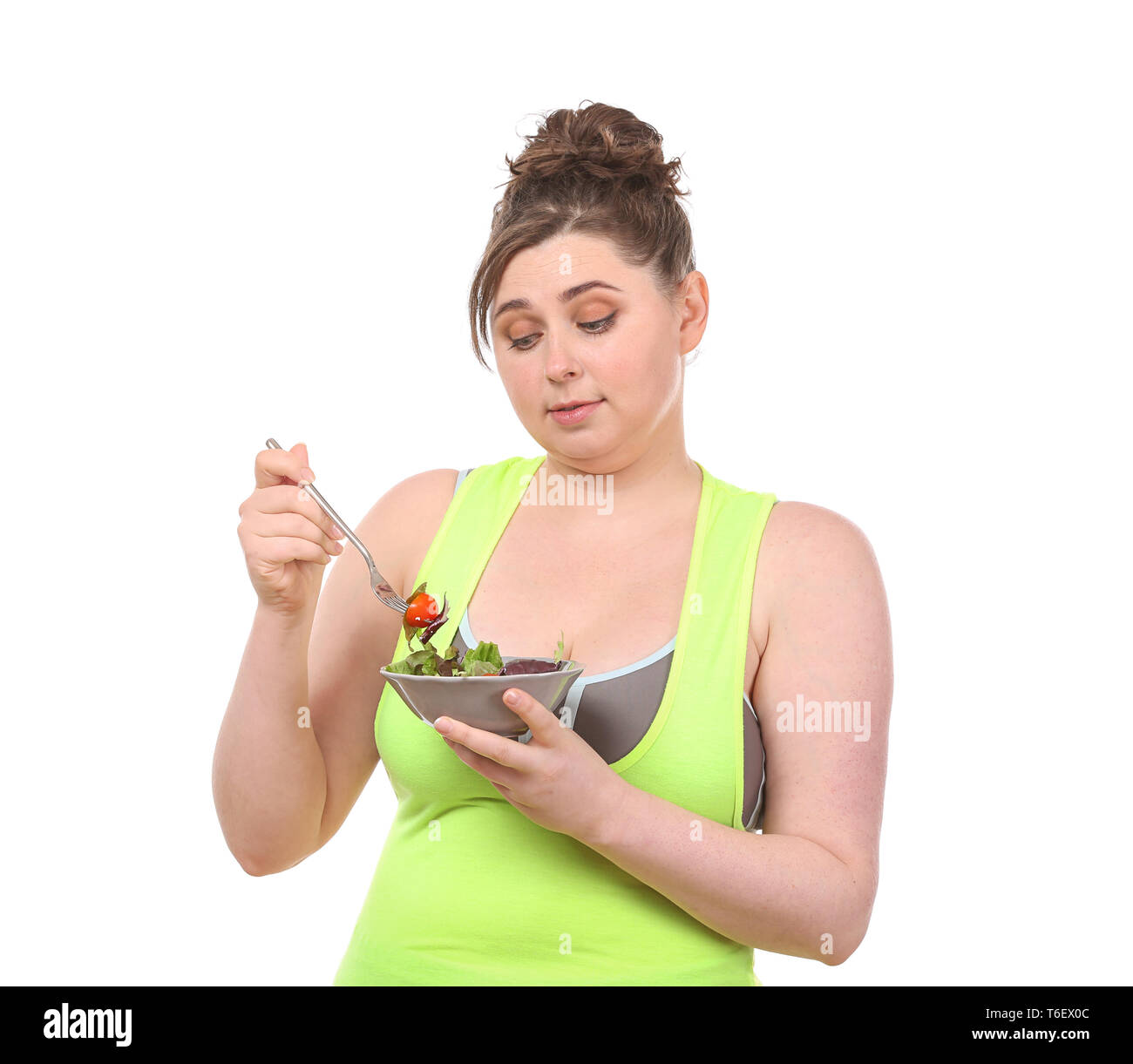 Young stout woman eating salad on white background. Diet food concept ...