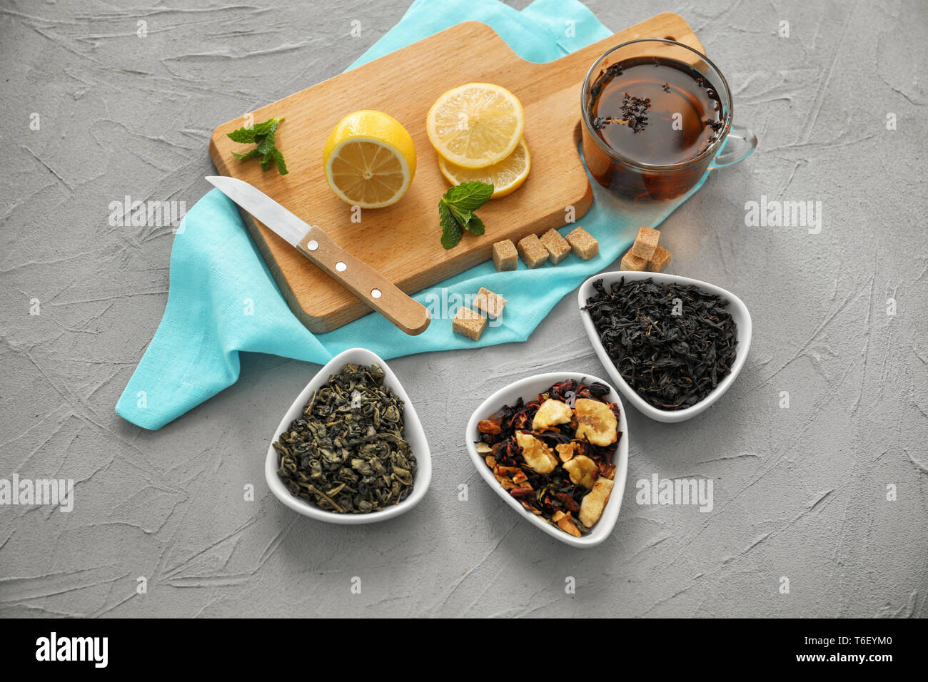 Different types of dry tea leaves and cup of aromatic beverage on table ...