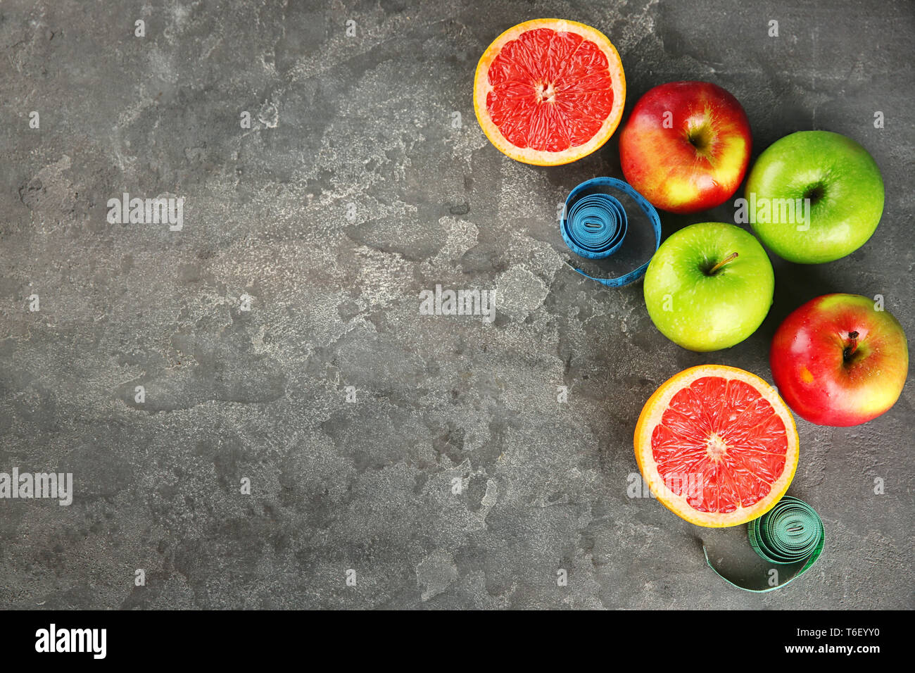 Fruits and measuring tapes on grey background. Diet food Stock Photo ...