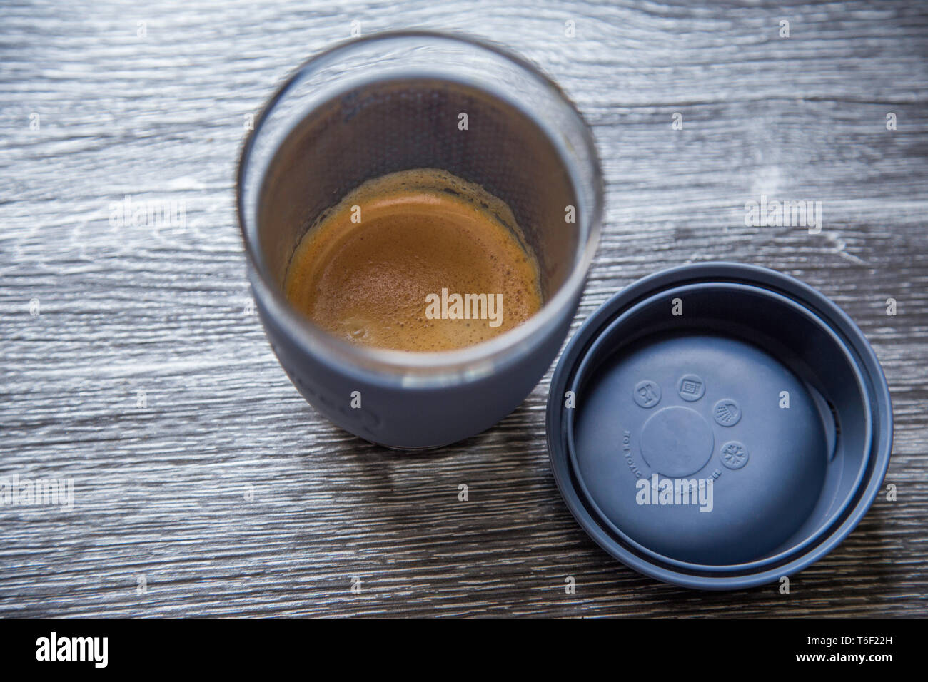 Top view of a reusable glass coffee cup sitting next to it's silicone ...