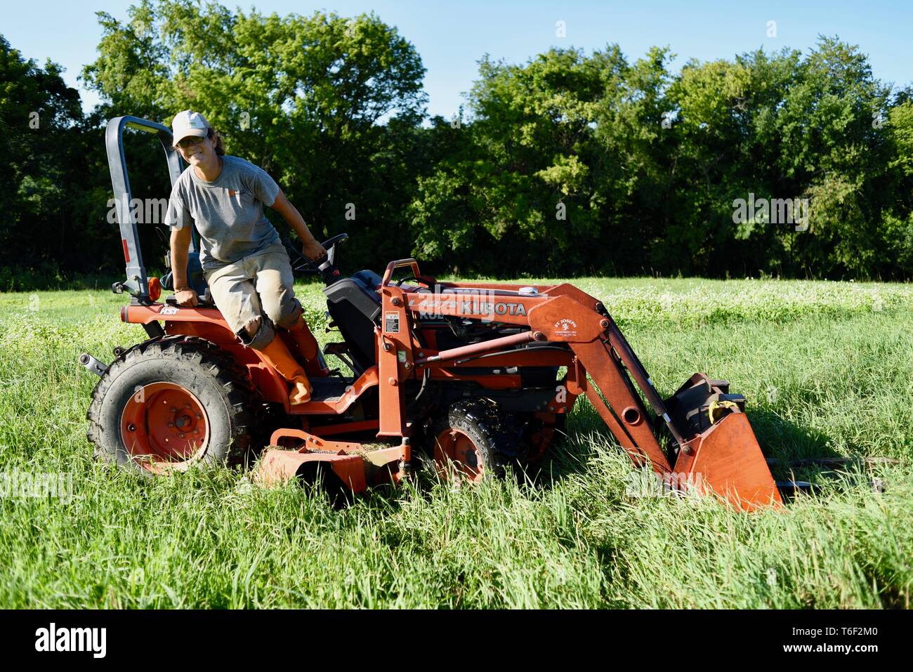 Hard working woman farmer standing up and hopping off after driving a ...