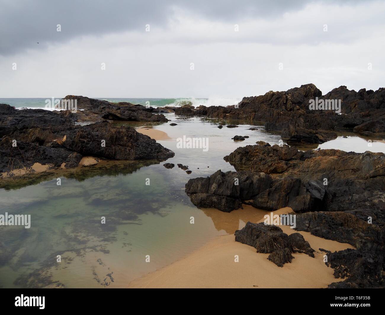 Stormy coastal weather, grey clouds looming over head as sea waves ...