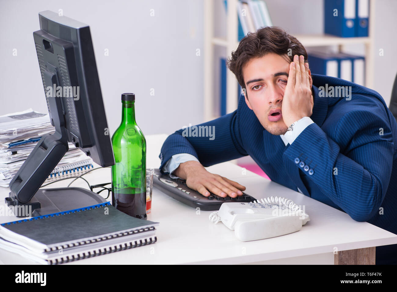 Young businessman employee drinking in the office at desk Stock Photo ...