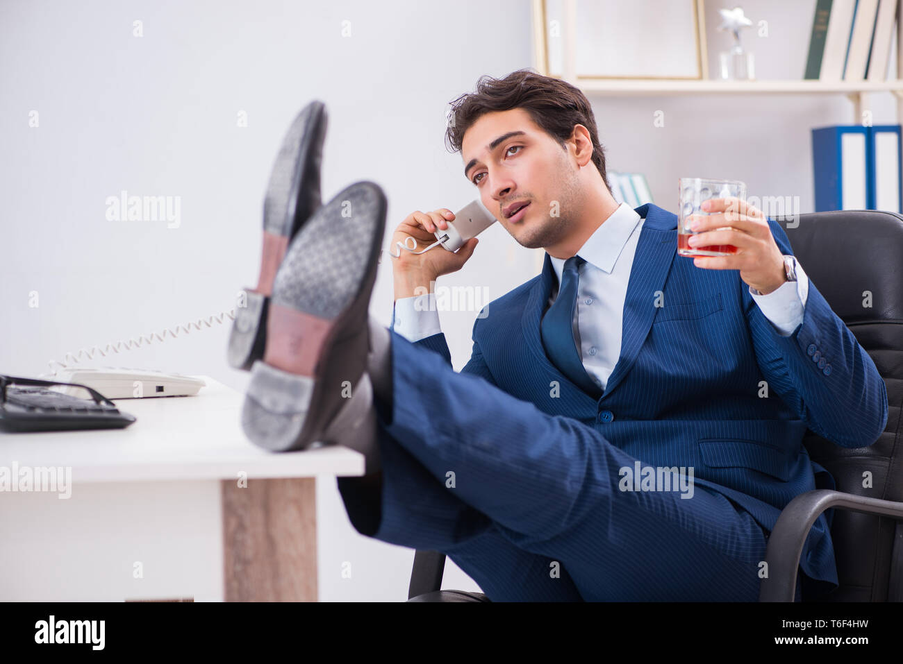Young businessman employee drinking in the office at desk Stock Photo ...