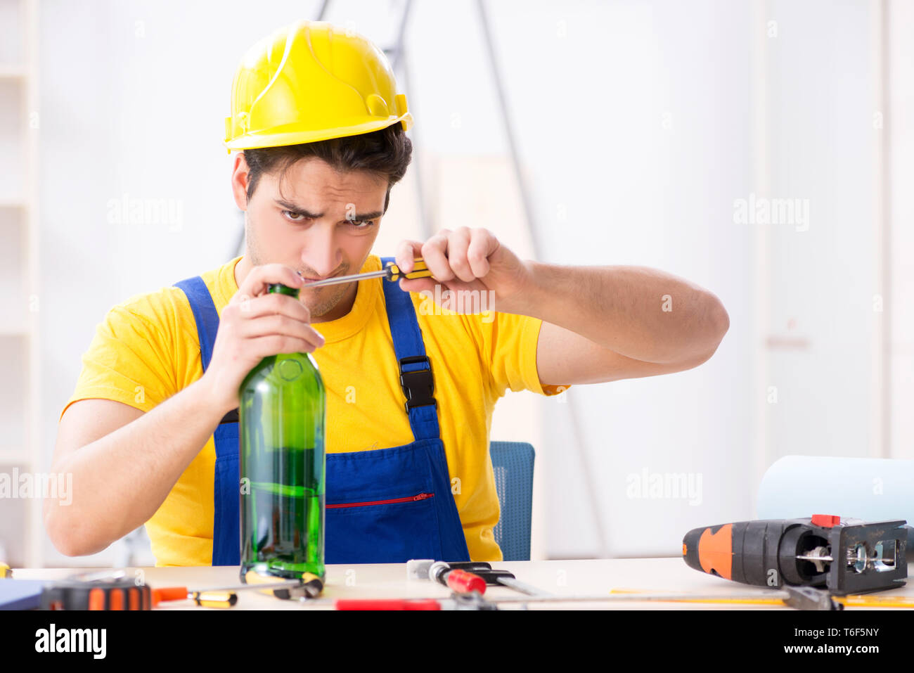 Drunk engineer working in the workshop Stock Photo - Alamy