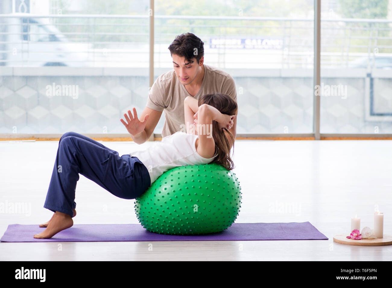 Personal coach helping woman in gym with stability ball Stock Photo - Alamy