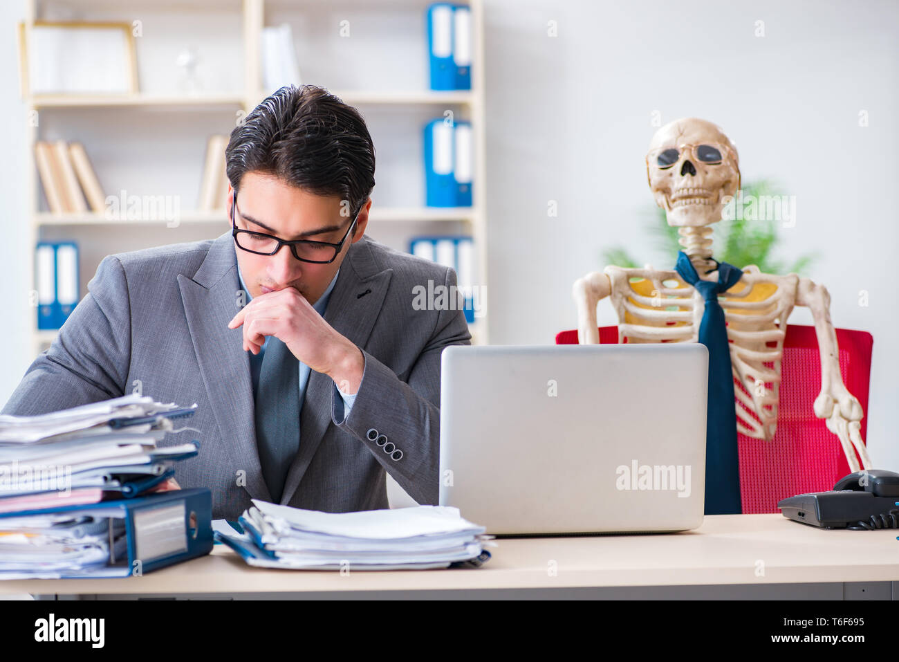 Businessman working with skeleton in office Stock Photo - Alamy