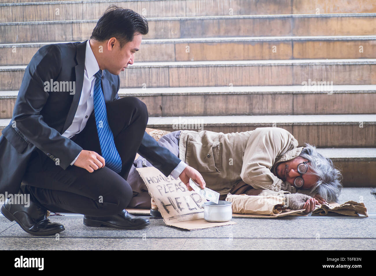 Businessman with suit donate some money in the metal bowl to help ...