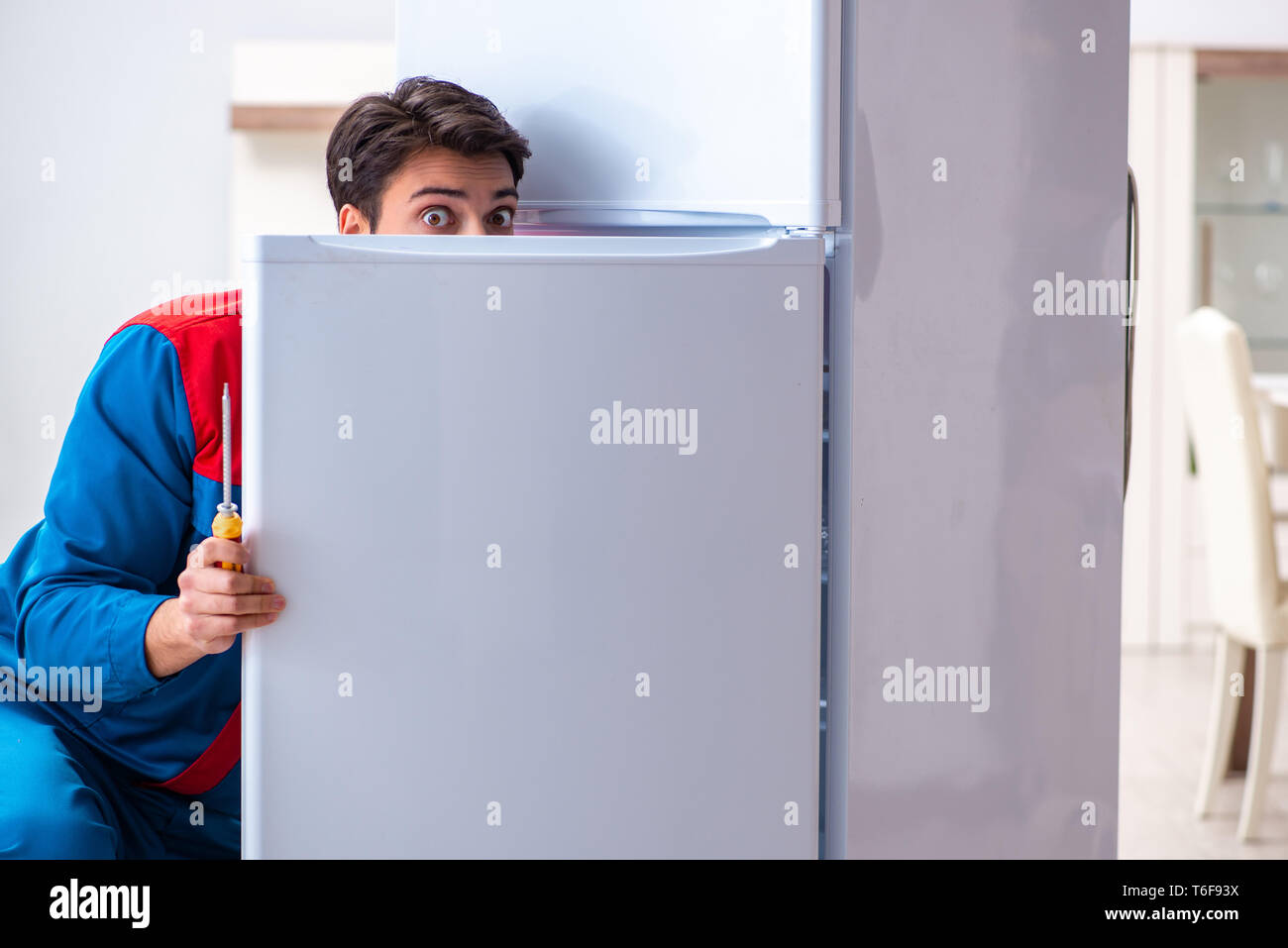 Professional contractor repairing broken fridge Stock Photo - Alamy