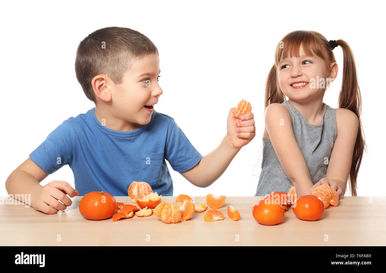 Cute little children eating citrus fruit at table on white background ...
