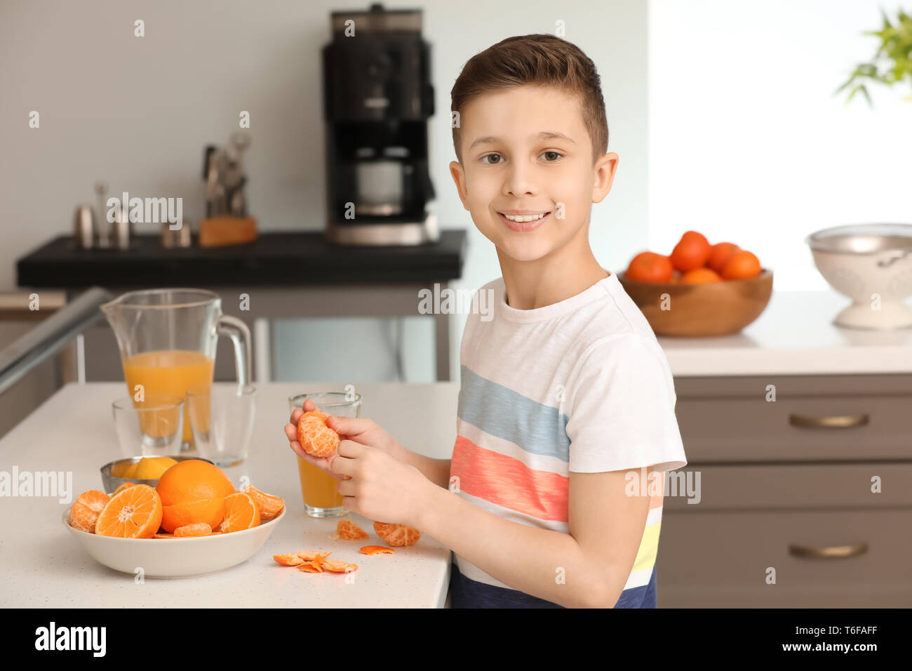 Funny little boy eating citrus fruit at home Stock Photo - Alamy