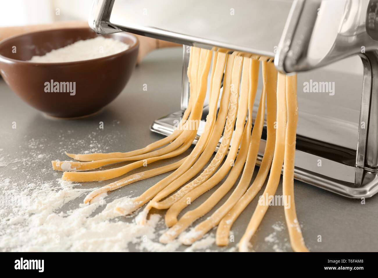 Metal pasta maker with dough on kitchen table Stock Photo - Alamy