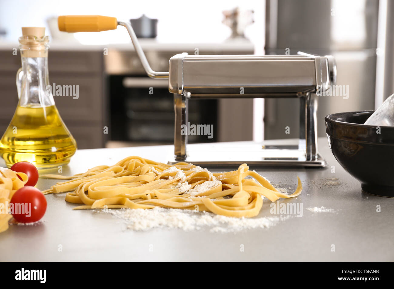 Metal pasta maker and uncooked noodles on kitchen table Stock Photo - Alamy