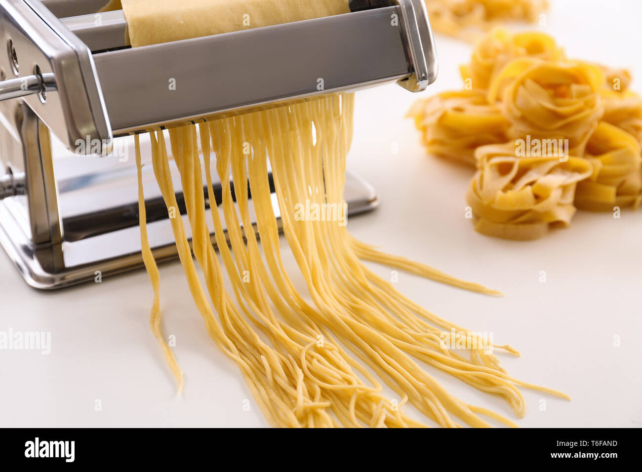 Metal pasta maker with dough on white background Stock Photo - Alamy