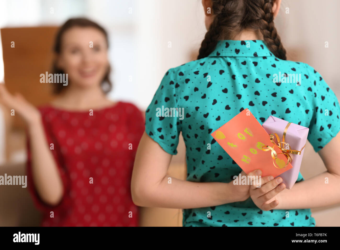 Little girl hiding gift for mother behind her back Stock Photo - Alamy