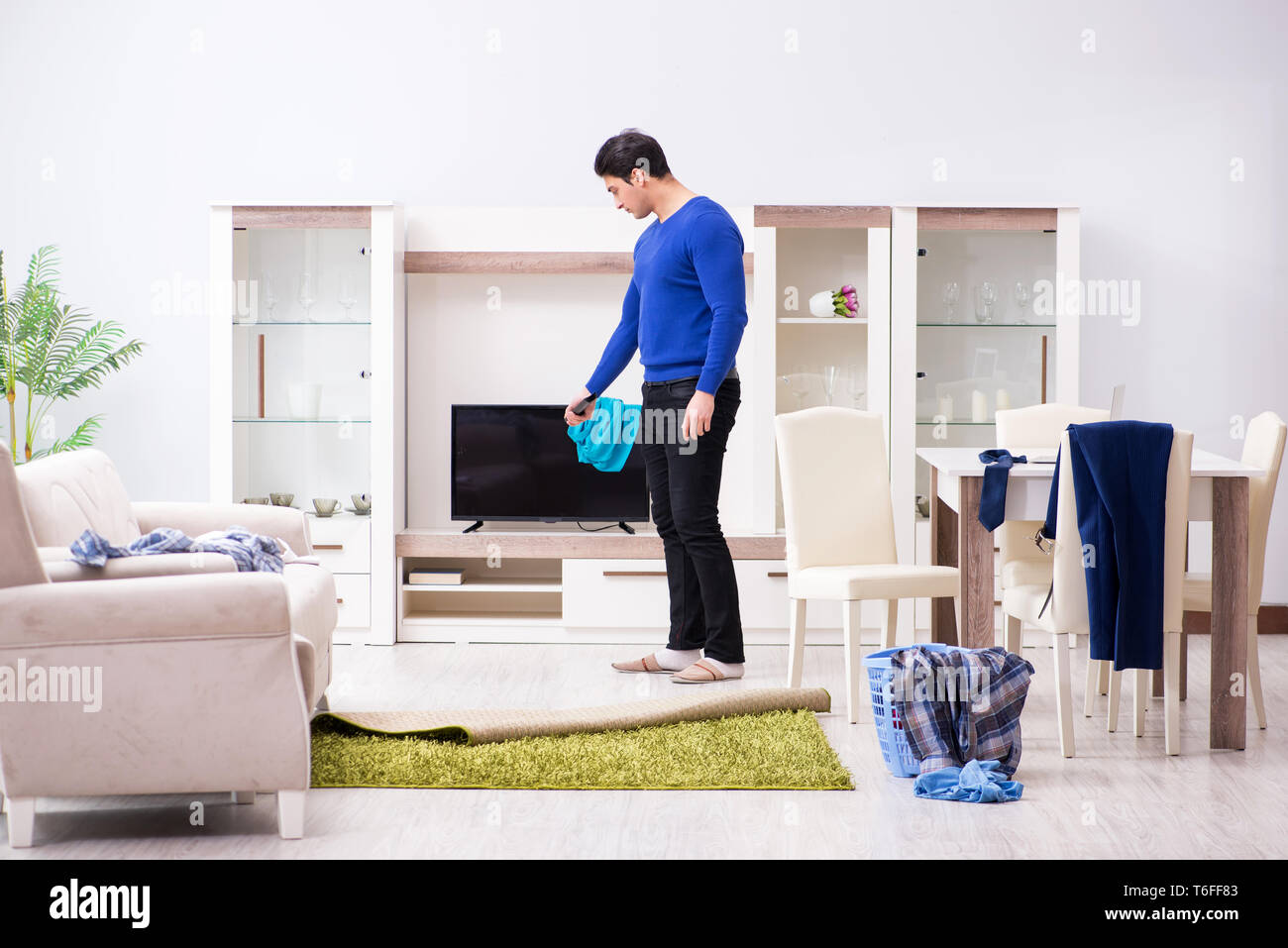 Young man collecting dirty clothing for laundry Stock Photo - Alamy