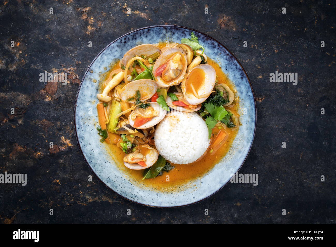 Traditional Thai kaeng phet red curry with clams and rice as top view ...