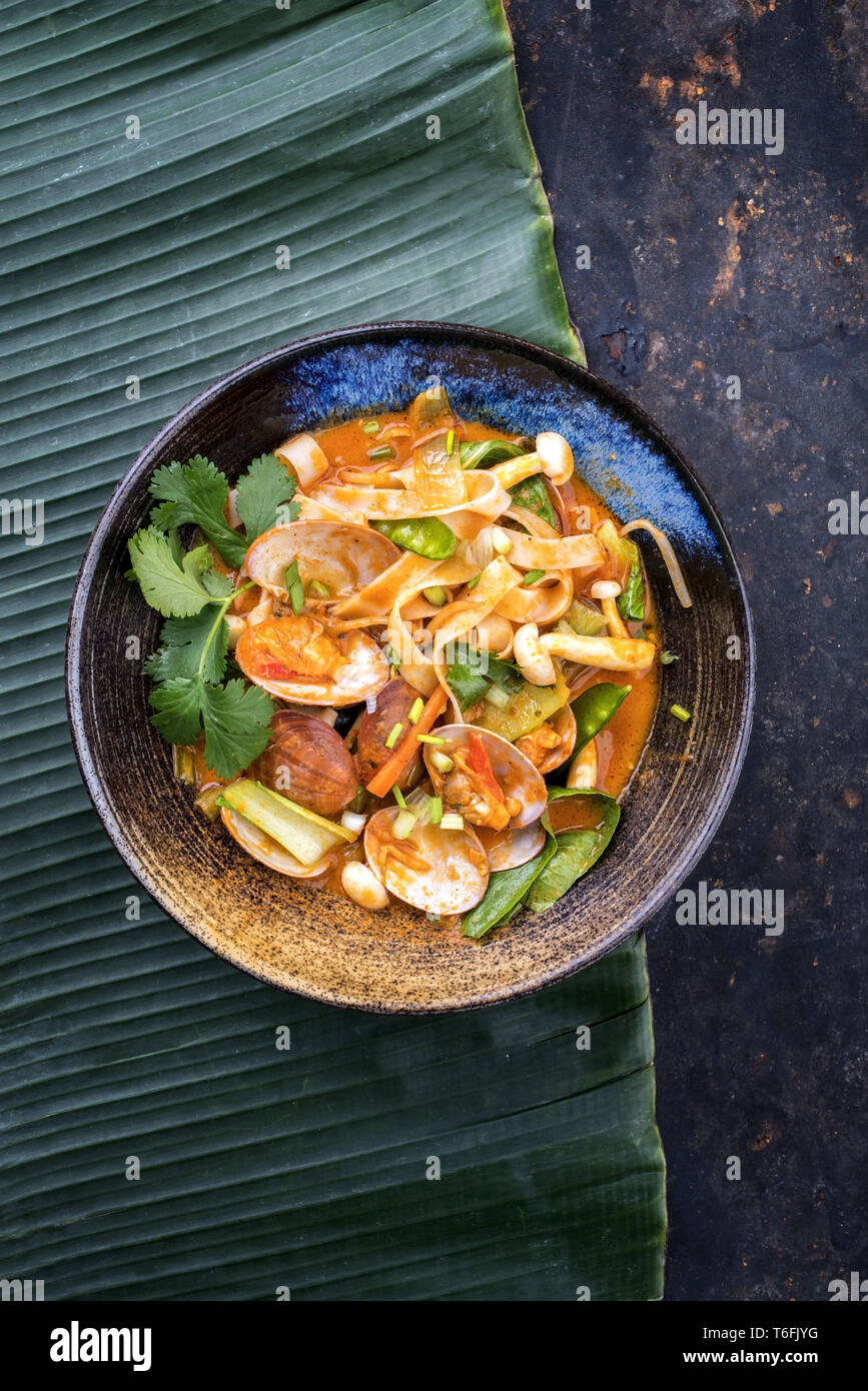 Traditional Thai kaeng phet red curry with clams and vegetable as top ...
