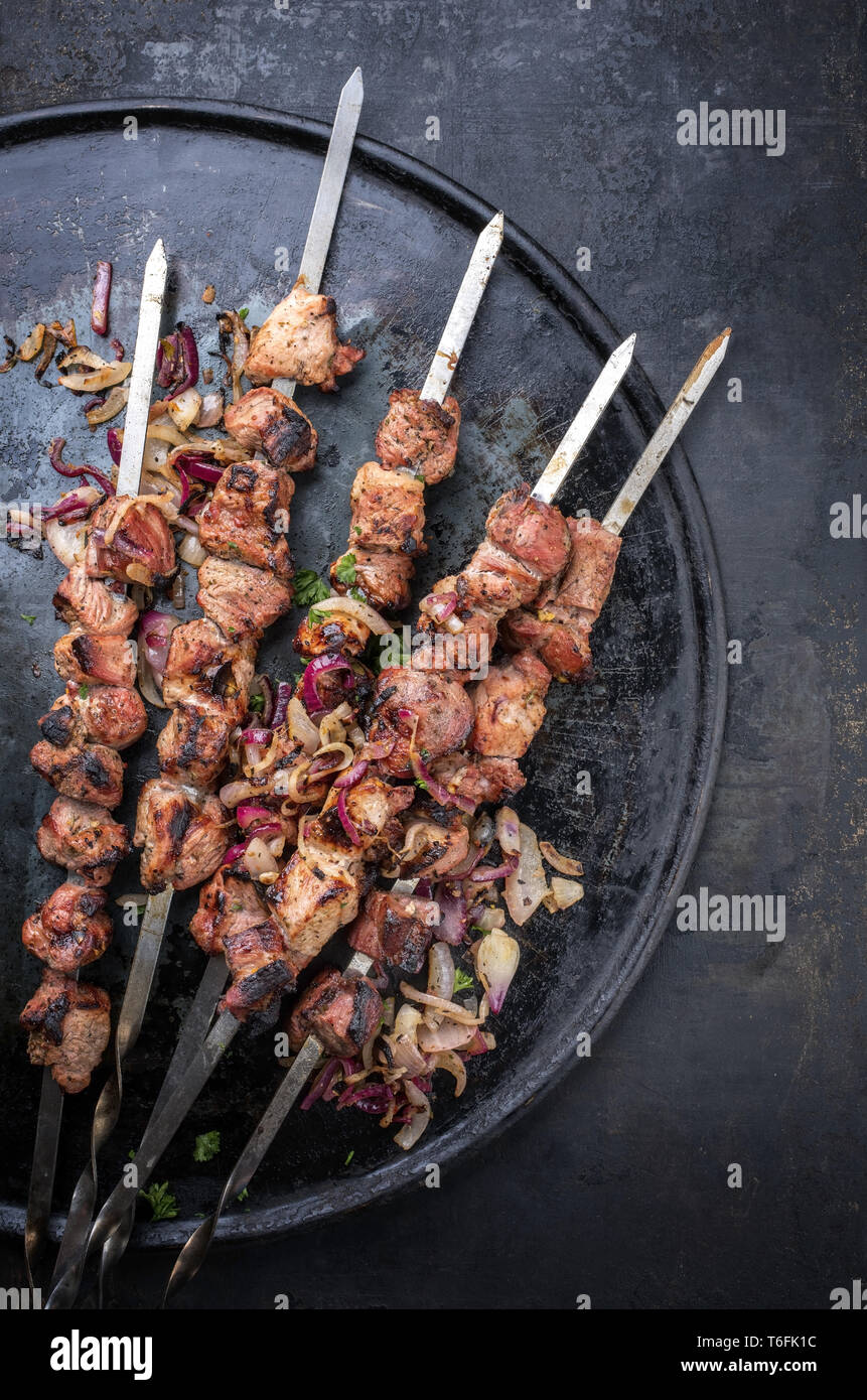 Traditional Russian shashlik on a barbecue skewer with roasted onion as ...