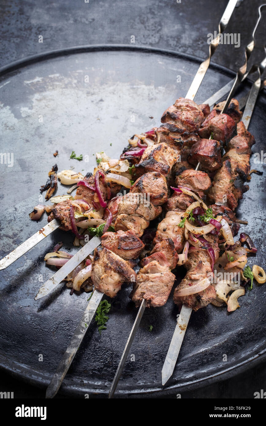 Traditional Russian shashlik on a barbecue skewer with roasted onion as ...